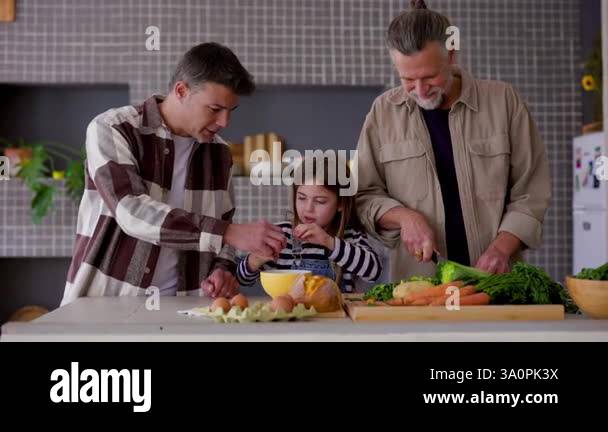 Multigenerational family gathering at kitchen counter, cooking together ...