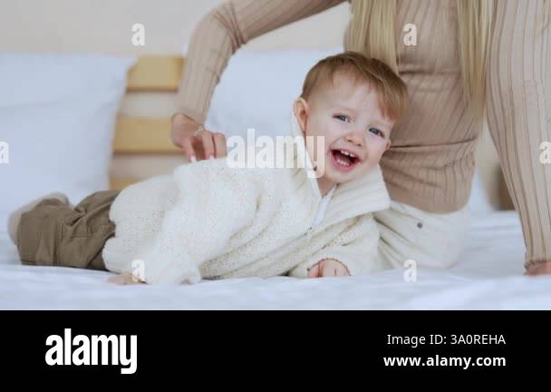 Unrecognized blonde woman plays with her little son. Mother touches and ...