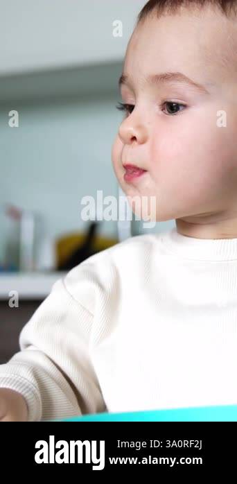 Beautiful child eating porridge from spoon. Cute little boy grabs a ...