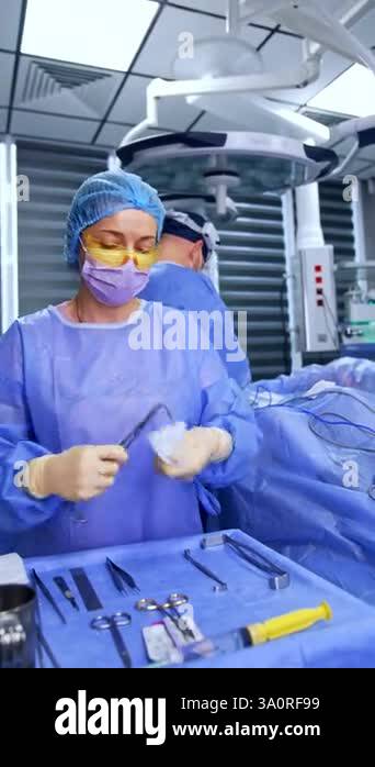 Female nurse wearing yellow protective glasses, cap, mask and blue robe ...