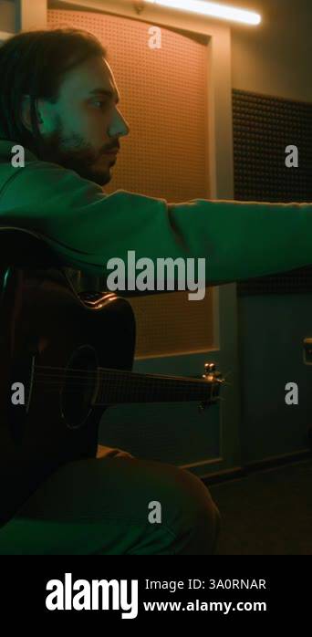 Vertical side shot of young adult Caucasian musician sitting with ...