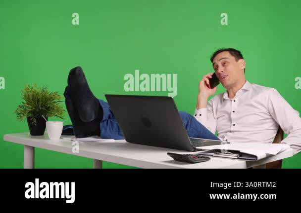Lazy employee is talking on the phone with his feet up on the table ...