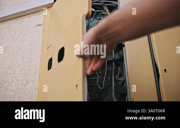 Close up hand gesture points inside open electrical panel box ...