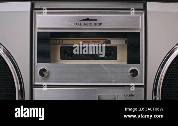 A hand opens the cassette player compartment of a vintage silver ...