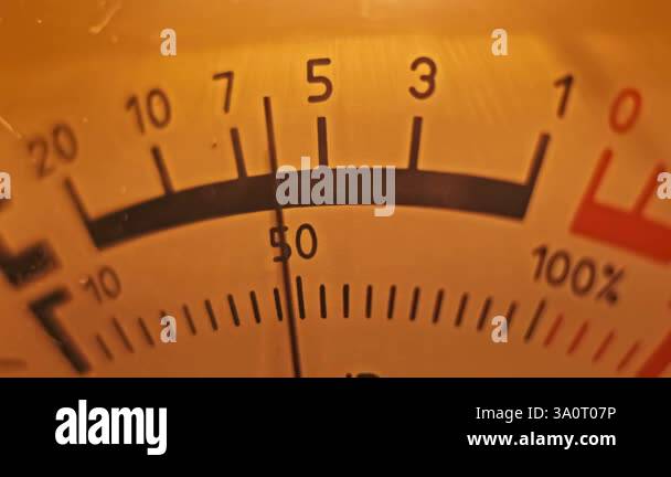 Detailed view of a single vintage VU meter, the needle pulsing back and ...