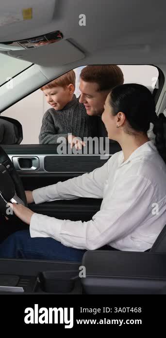 A happy family examines the features of their new right-hand drive car ...