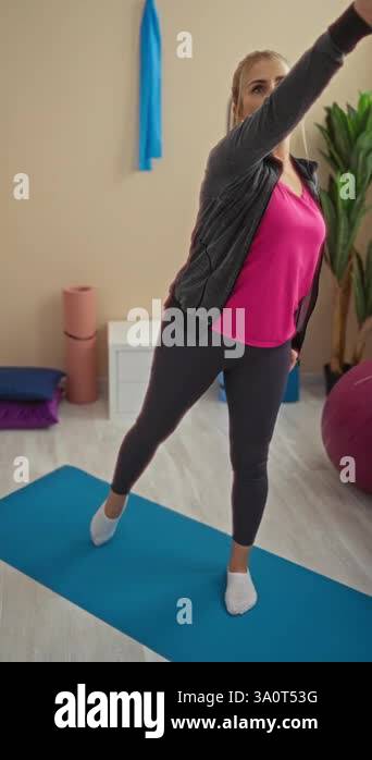 Woman exercising in a gym wearing a pink top and black leggings ...
