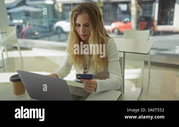 Woman multitasking in a bright office setting with a laptop and credit ...