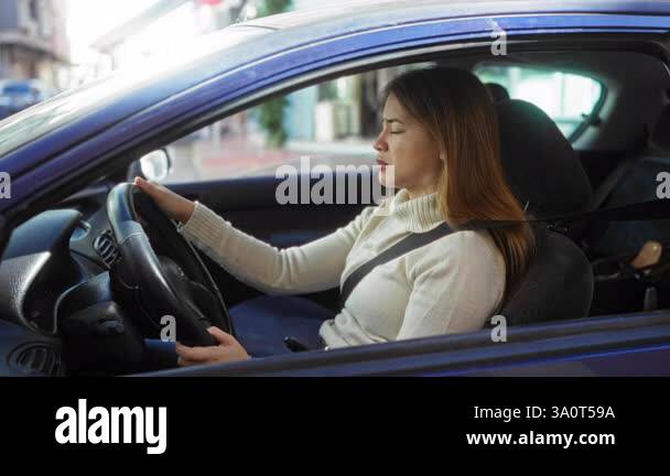 Woman driving car in urban street, appearing stressed while wearing ...