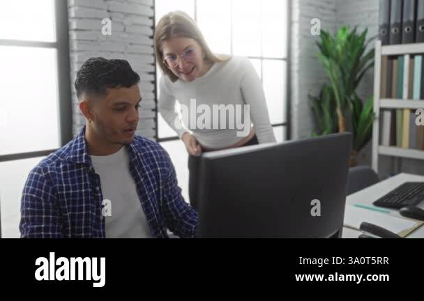 Man and woman smiling and collaborating at a computer in a bright ...