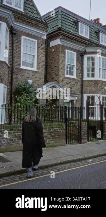 Woman strolling past charming brick houses in chelsea london uk on a ...