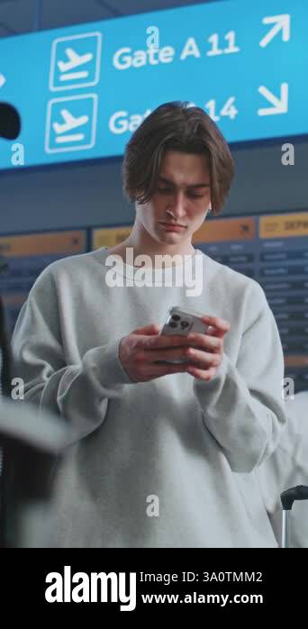 Crowded Airport Terminal: Young Man Scrolling on Mobile Phone, Waiting ...