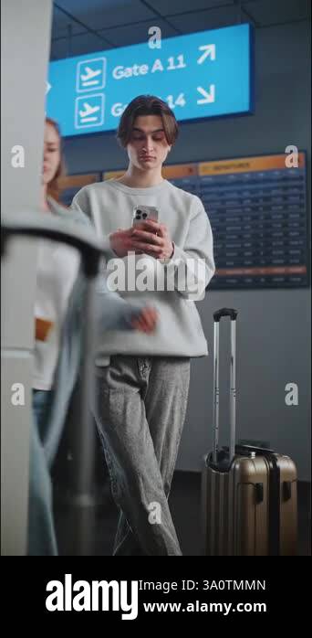 Crowded Airport Terminal: Young Man Scrolling on Mobile Phone, Waiting ...