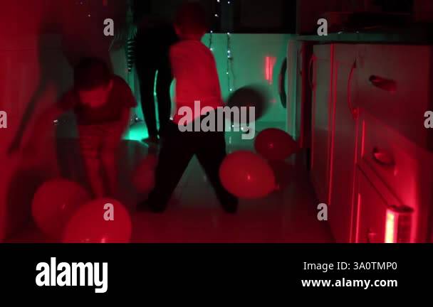 Kids enjoy a playful evening, chasing balloons under colorful lights in ...