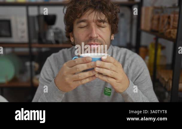 Young man enjoying a coffee break in relaxed office setting with closed ...