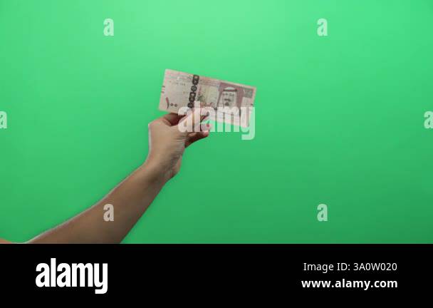 Man holding saudi arabia riyal banknote against isolated green ...