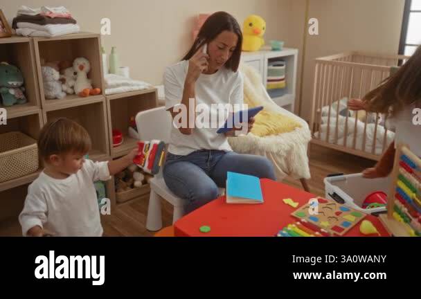 Woman multitasking with phone and tablet in cozy nursery with child ...