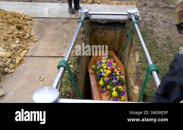 lowering of the casket coffin into the burial ground at the cemetery ...