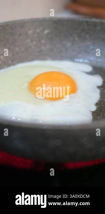 Watch as an egg is cracked and cooked in a skillet over heat Stock ...
