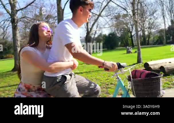 Loving couple pedaling side by side through lush park greenery, sharing ...
