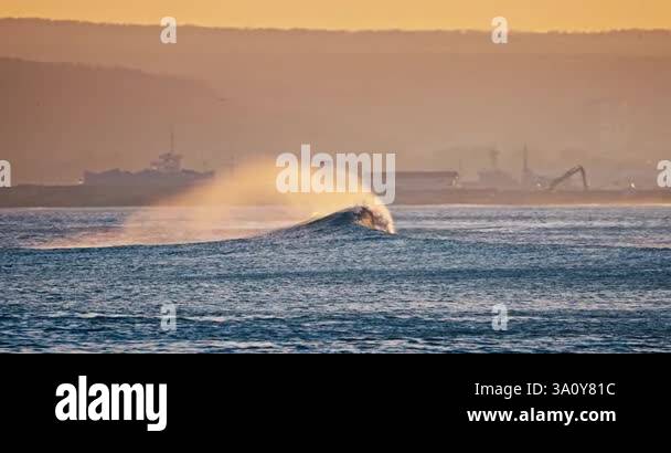 Scenic sea wave at sunrise with sunlight horizon and industrial harbor ...