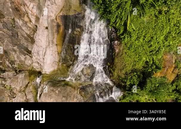 Steep waterfall flowing through lush jungle terrain and rocky cliffs ...