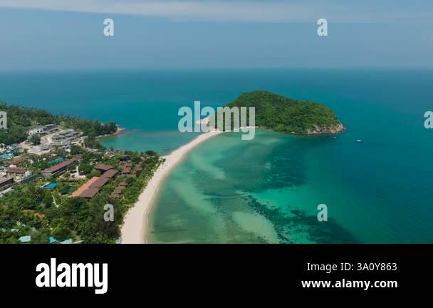 A pristine beach with a green island surrounded by turquoise waters ...