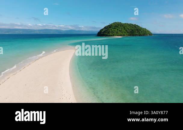 A tropical island surrounded by calm turquoise waters and a sandbar ...