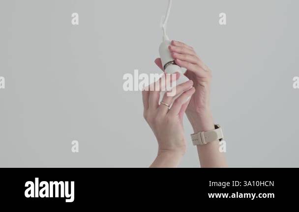 Person installing an LED light bulb in a ceiling socket, home ...