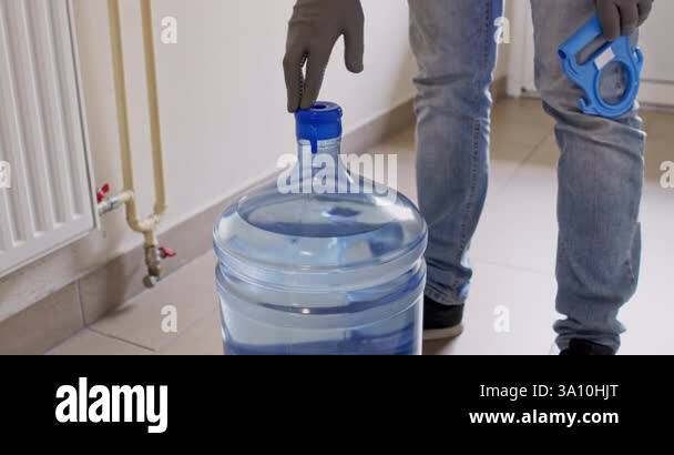 Cooler water bottle cap falls off as courier lifts container. Guy in ...