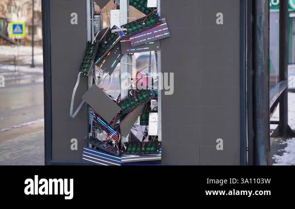 A heavily damaged digital billboard at a bus stop with broken LED ...