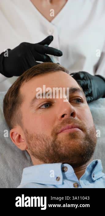 A man undergoes a mesotherapy scalp injection at a trichologist office ...