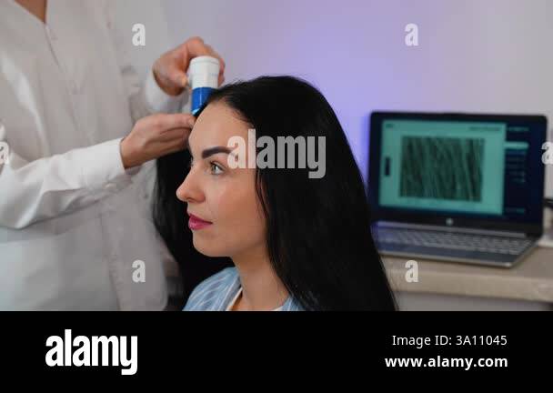 A trichologist conducts a hair analysis on a woman using a digital ...