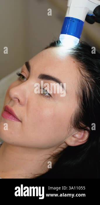 A trichologist conducts a hair analysis on a woman using a digital ...