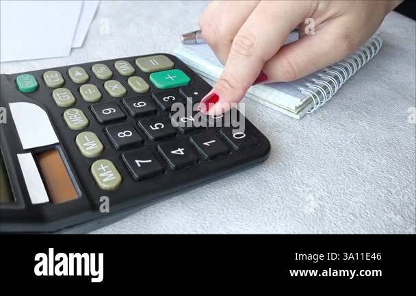 A woman's hand counts the numbers on a calculator. The accountant's job ...
