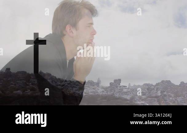 Man praying with hands covering face over cross and rocky landscape ...