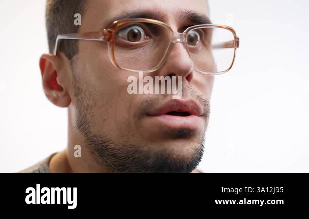 A man wearing glasses dramatically widens his eyes, creating a ...