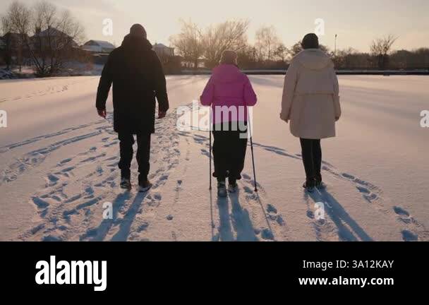 Senior woman practicing Nordic walking on a frozen lake at sunset ...