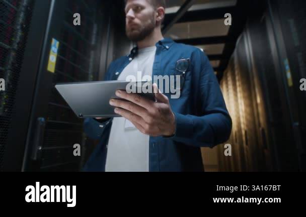Low angle tilt up shot of young concentrated Caucasian male IT engineer ...