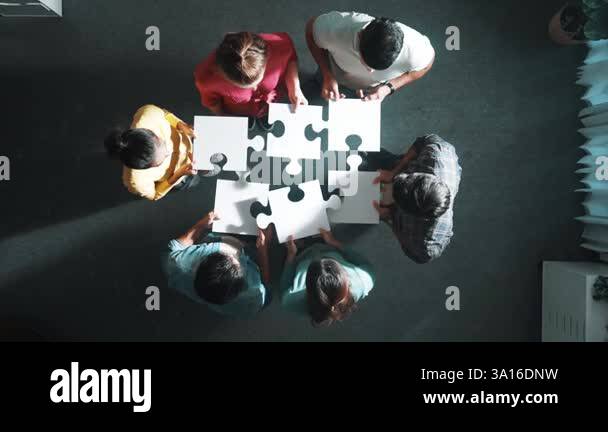 Top down view of business people gathering jigsaw together at meeting ...