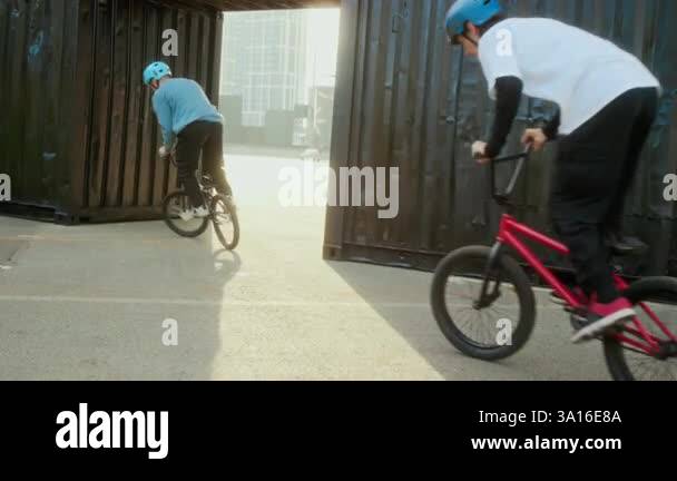 BMX rider in streetwear and helmet riding, jumping with bike and ...