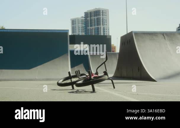 Slow shutter effect footage of BMX rider jumping over bike lying on ...