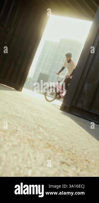 Vertical shot of BMX rider performing 180 trick at entrance of skate ...
