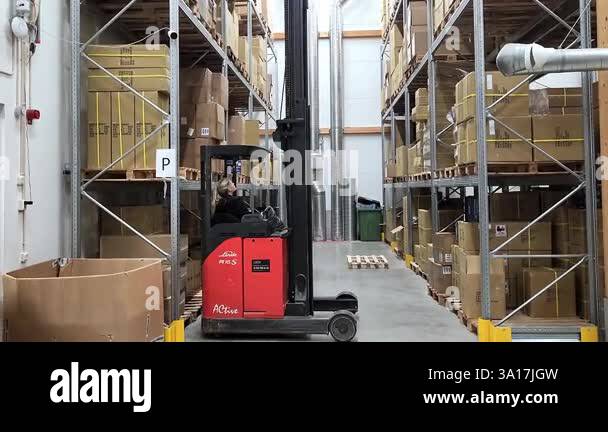 Female forklift operator moving stacked boxes in warehouse with tall ...