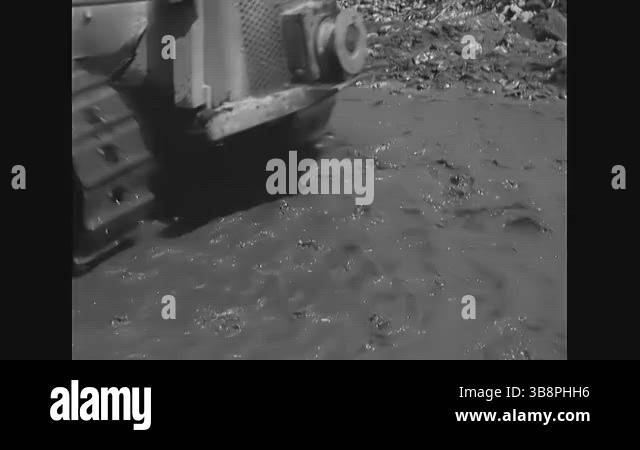 KISKA - 1946 - Caterpillar tractors and trailers drive through water, and a caterpillar driver ...