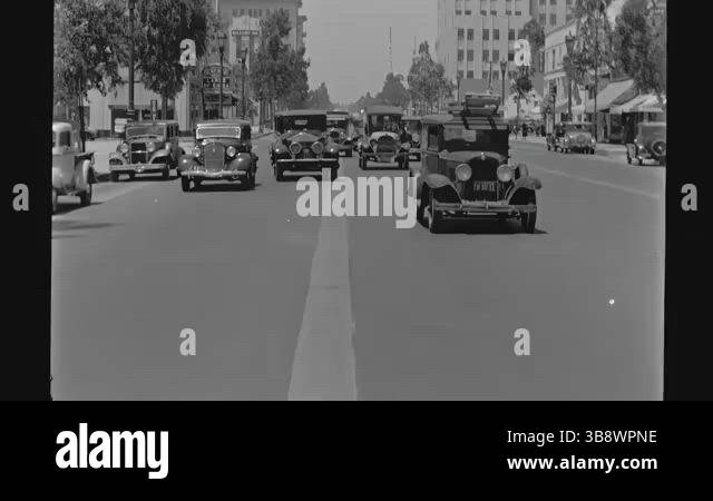 BEVERLY HILLS - 1935 - Front-facing view of cars driving up a busy ...