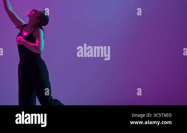 A young female dancer in a black outfit performs an expressive ...