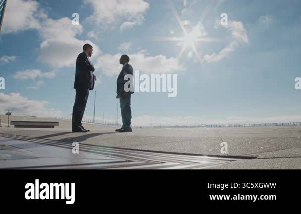 Low angle shot of two businessmen in suits shaking hands on sun ...