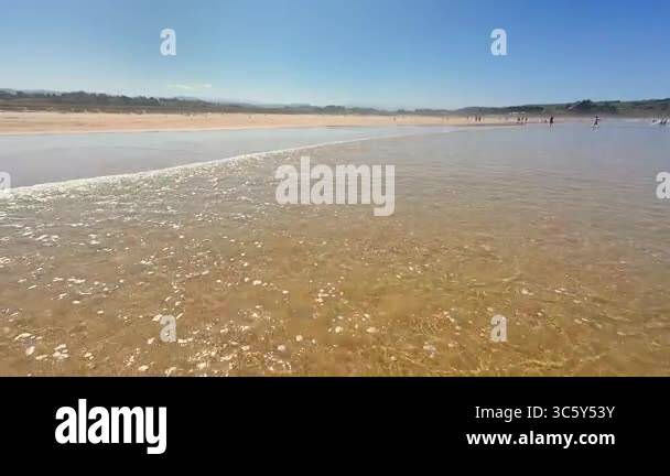 A peaceful beach scene with soft waves under a clear blue sky, perfect ...