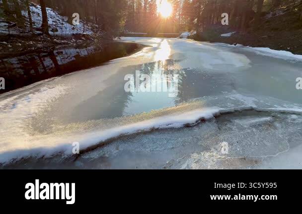A tranquil scene with a partially frozen river reflecting the bright ...